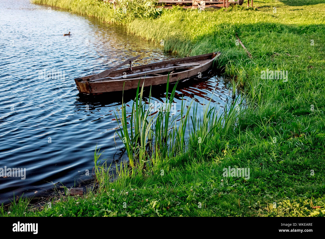 A small wooden rowing boat with a broken bottom on a calm lake near the ...