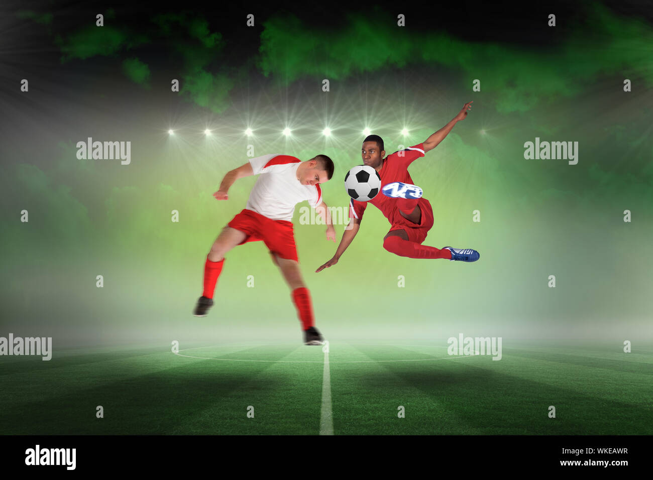 Football players tackling for the ball against football pitch under ...