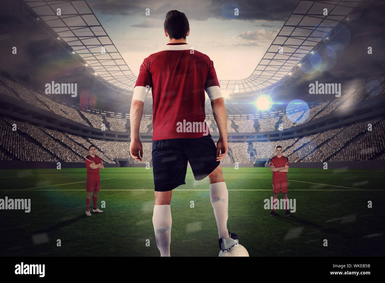 Football player in red with ball facing opposition against large ...