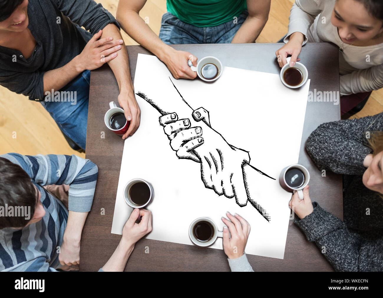 People sitting around table drinking coffee with page showing hands ...