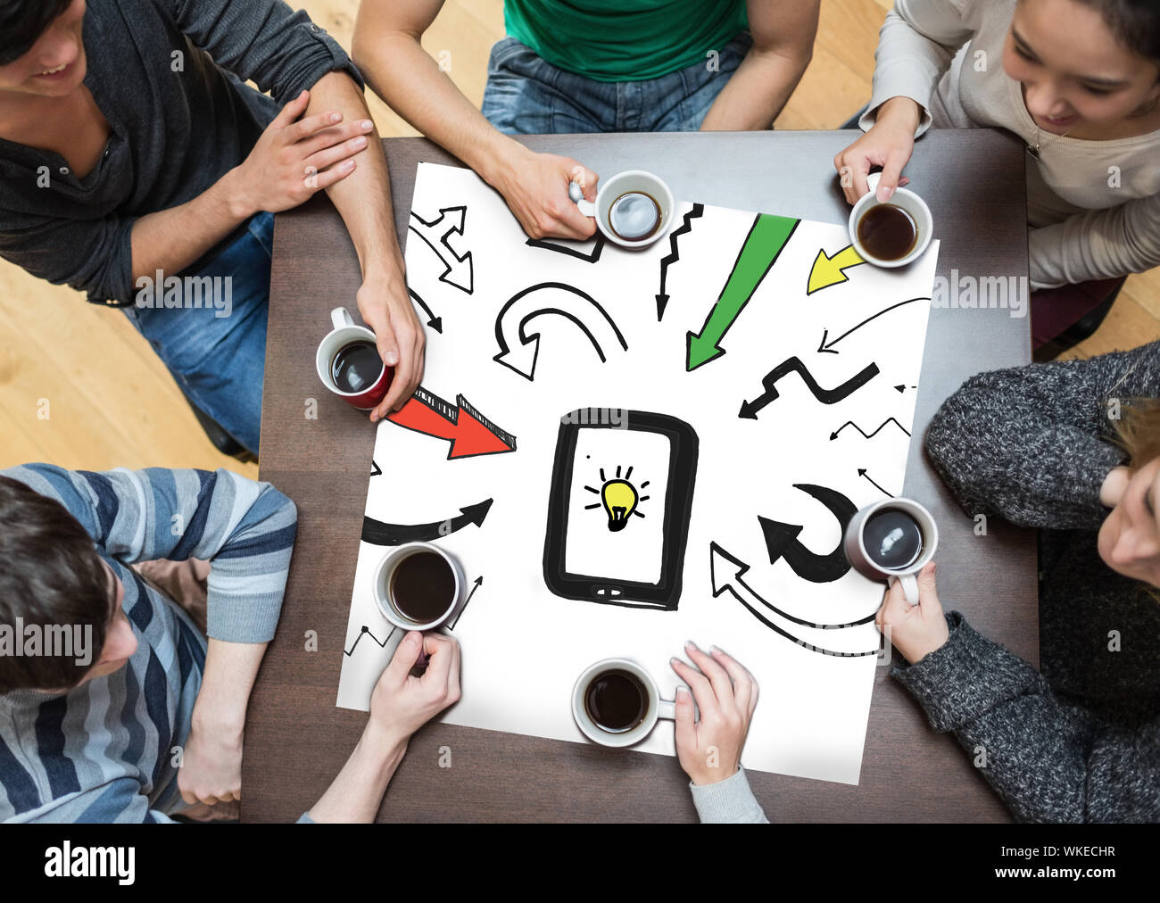 People sitting around table drinking coffee with page showing ...