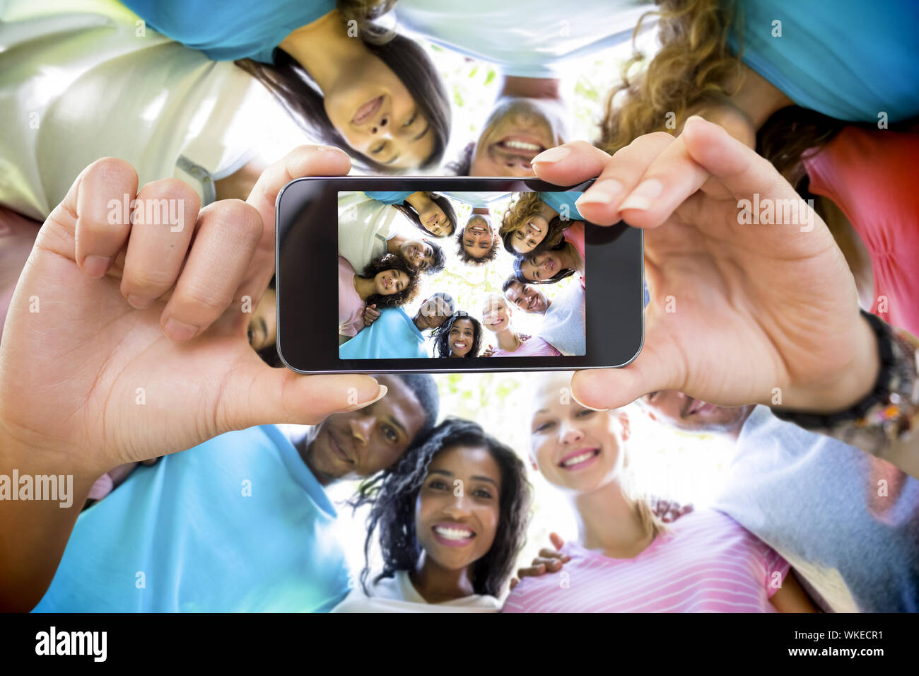 Hand holding smartphone showing friends forming huddle Stock Photo - Alamy