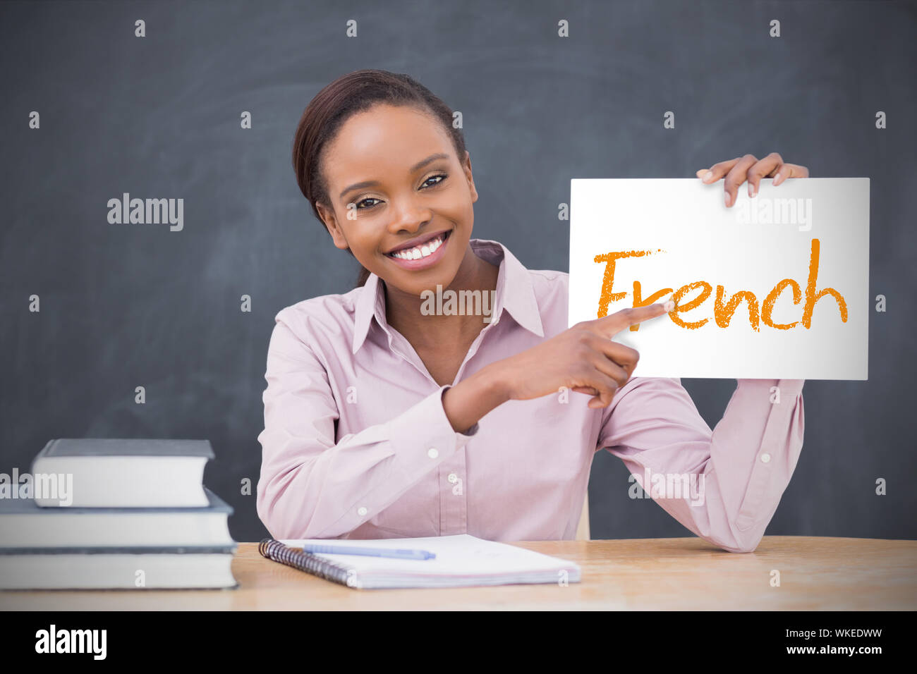 Happy teacher holding page showing french in her classroom at school ...