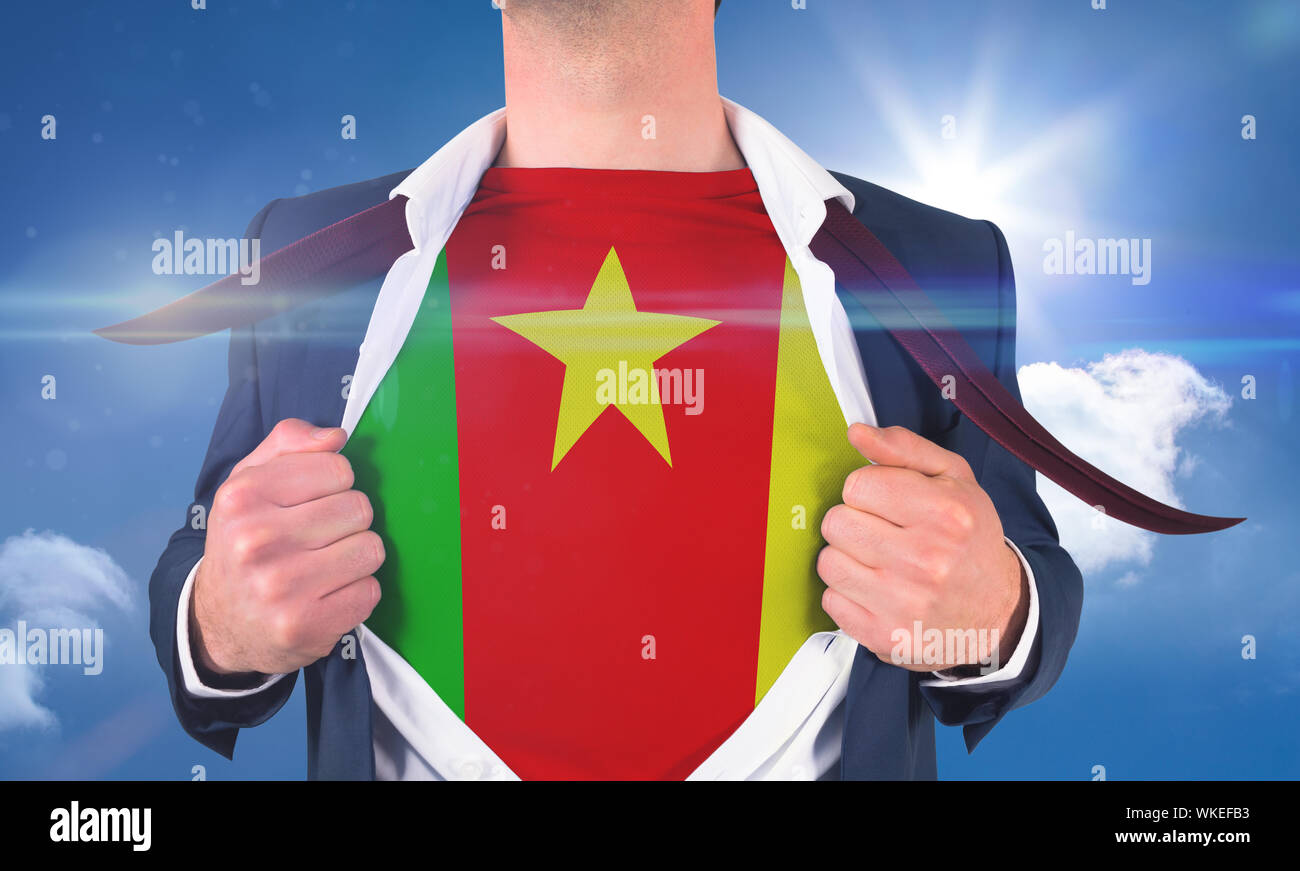 Businessman opening shirt to reveal cameroon flag against bright blue ...