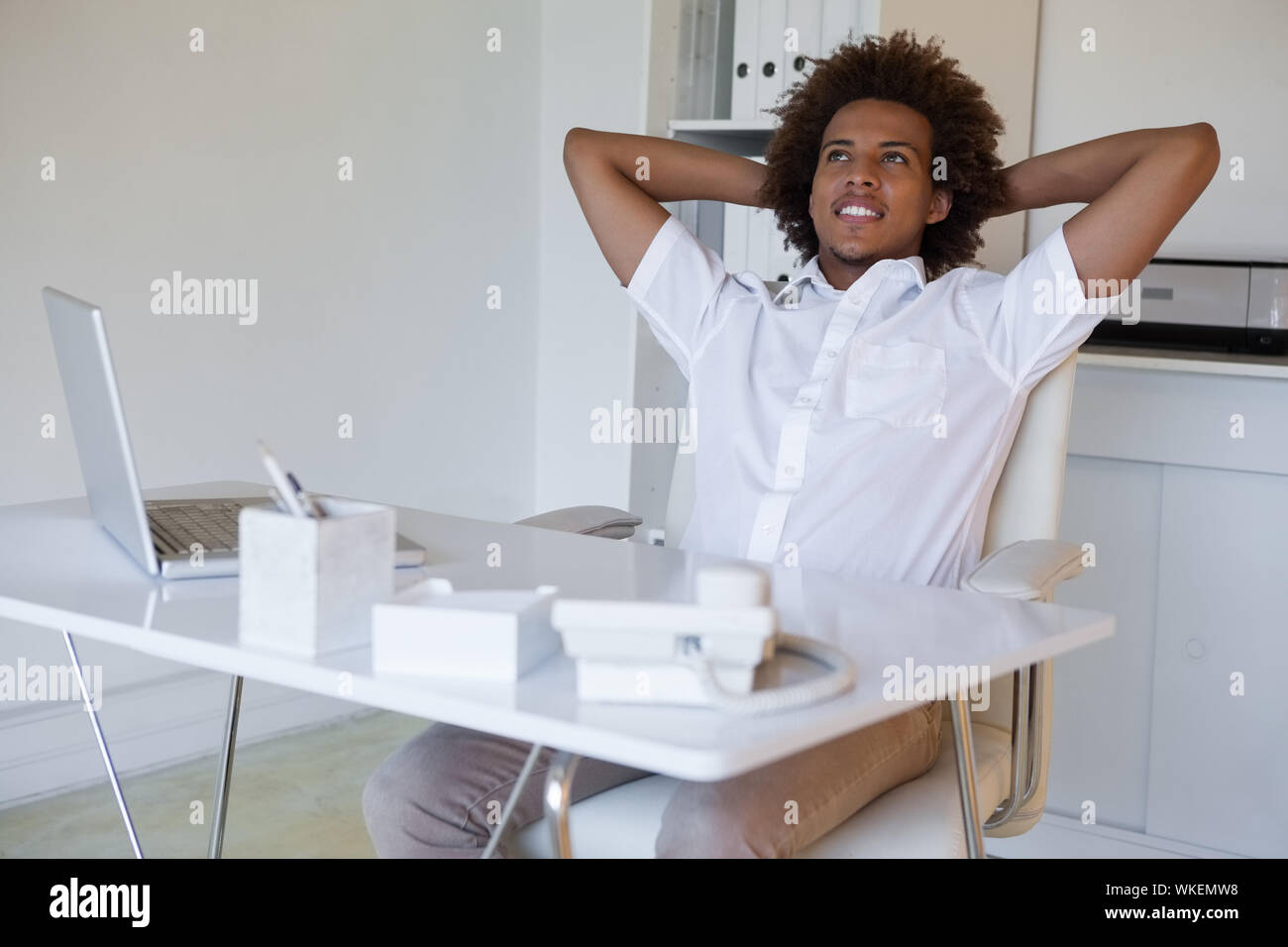 Relaxed casual businessman leaning back at his desk in his office Stock ...