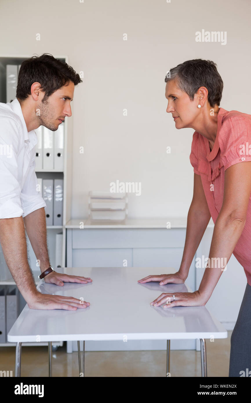 Casual business team facing off at desk in the office Stock Photo - Alamy