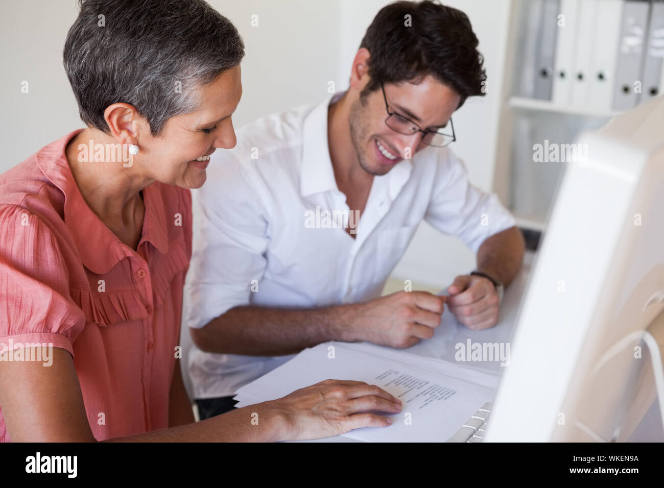 Casual business team working together at desk using computer in the ...