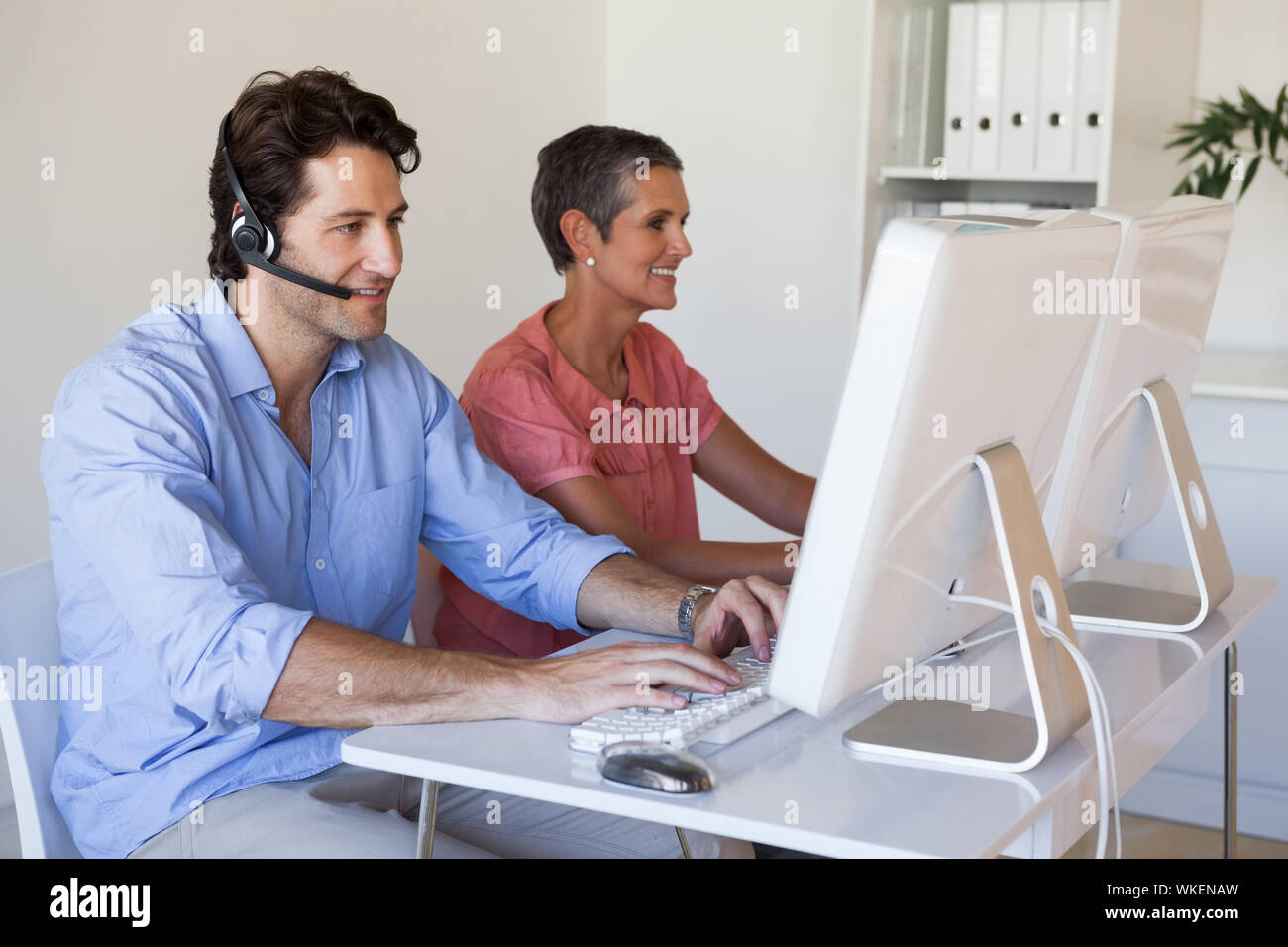 Casual business team working at desk using computers with man using ...