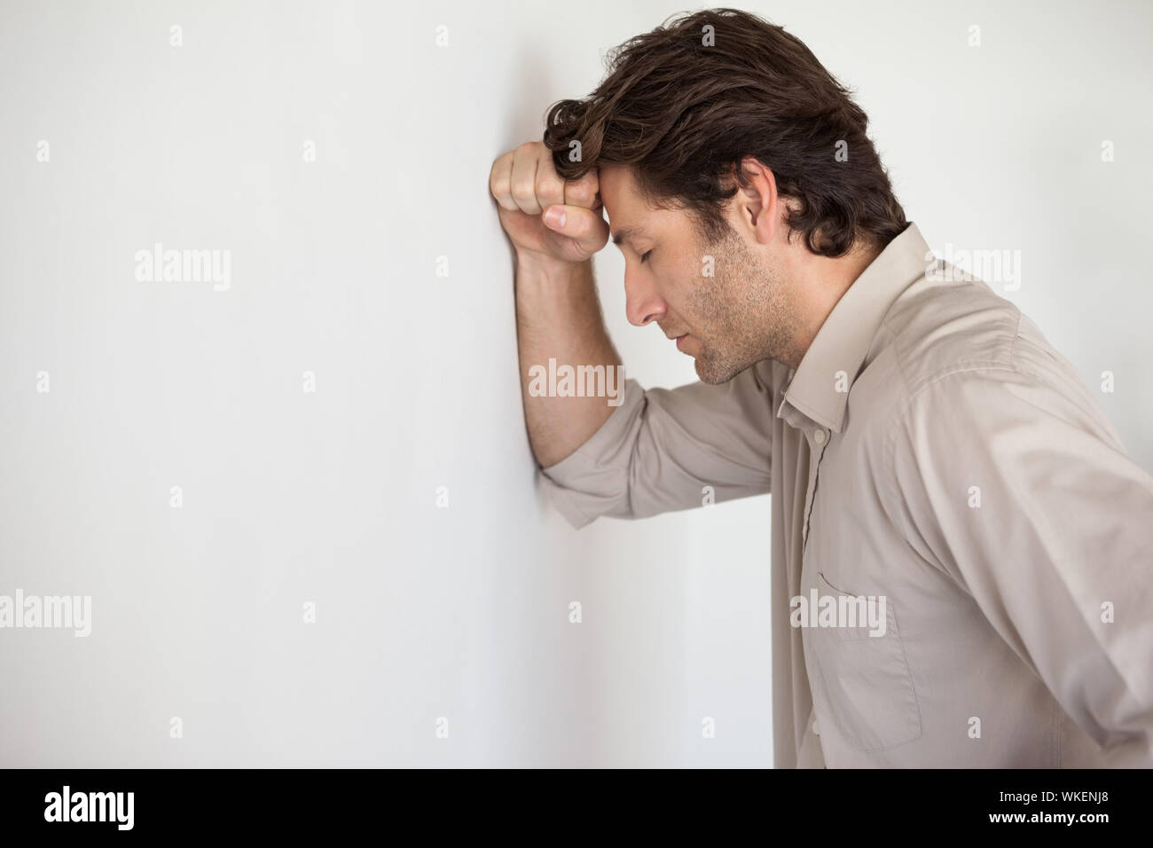 Casual worried businessman leaning head on wall in his office Stock ...
