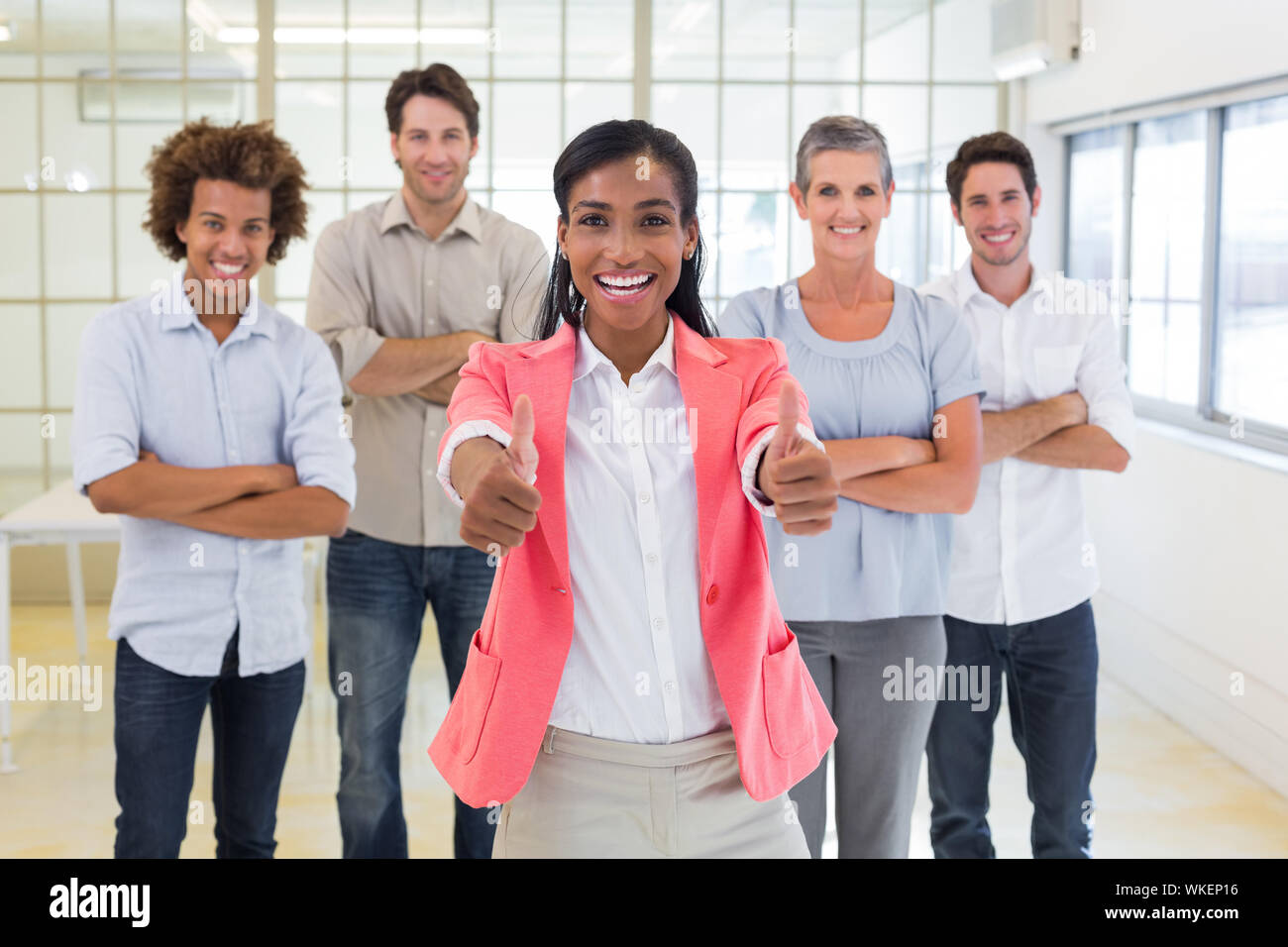 Happy team of workers giving thumbs up in the office Stock Photo - Alamy