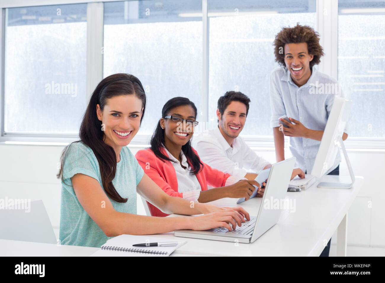 Workers using technology and smiling to the camera in the office Stock ...