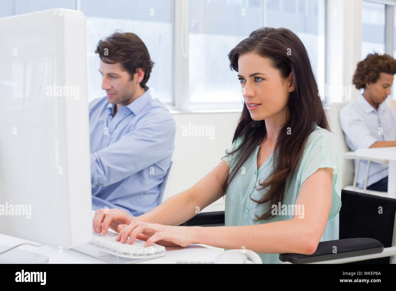 Attractive woman in wheelchair working hard on computer in the office ...