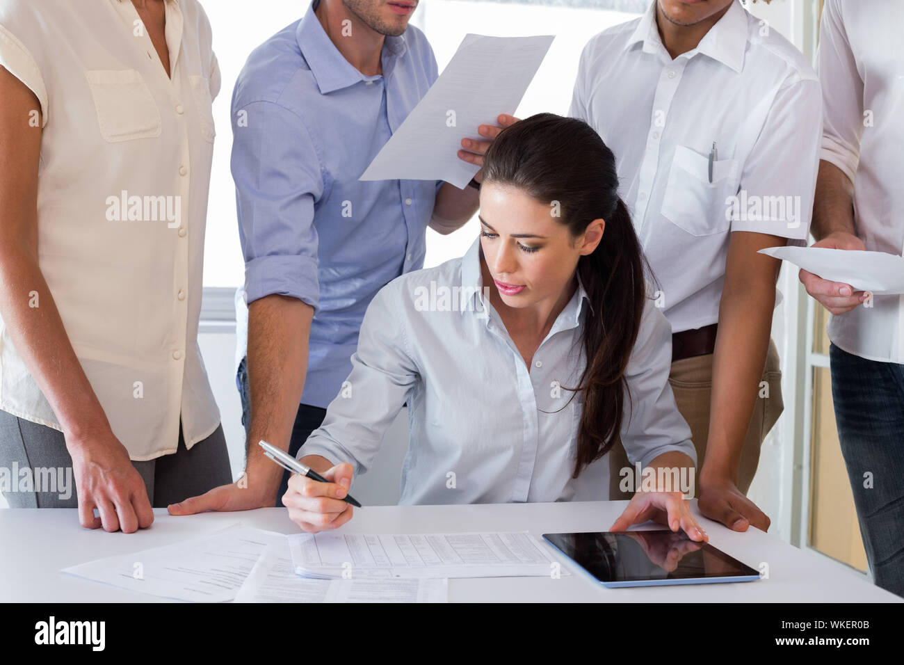 Attractive businesswoman working hard on papers amongst fellow ...