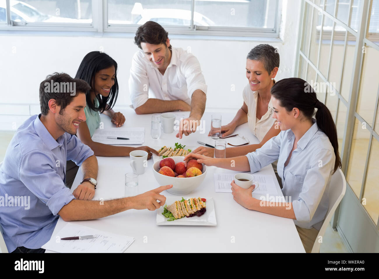 Business people eating sandwiches and fruit for lunch in the office ...