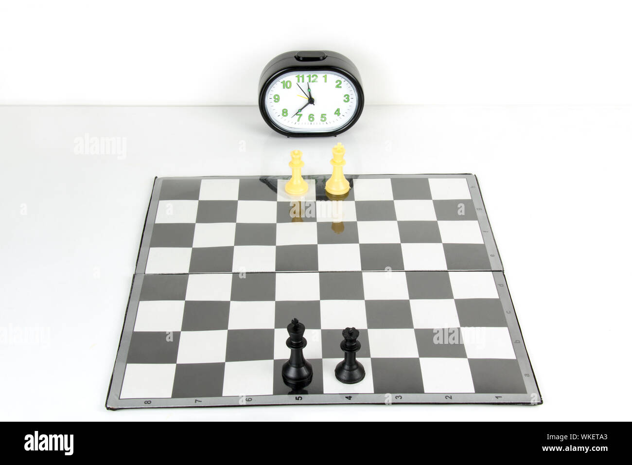 Chess pieces on a checkered board with clock Stock Photo - Alamy