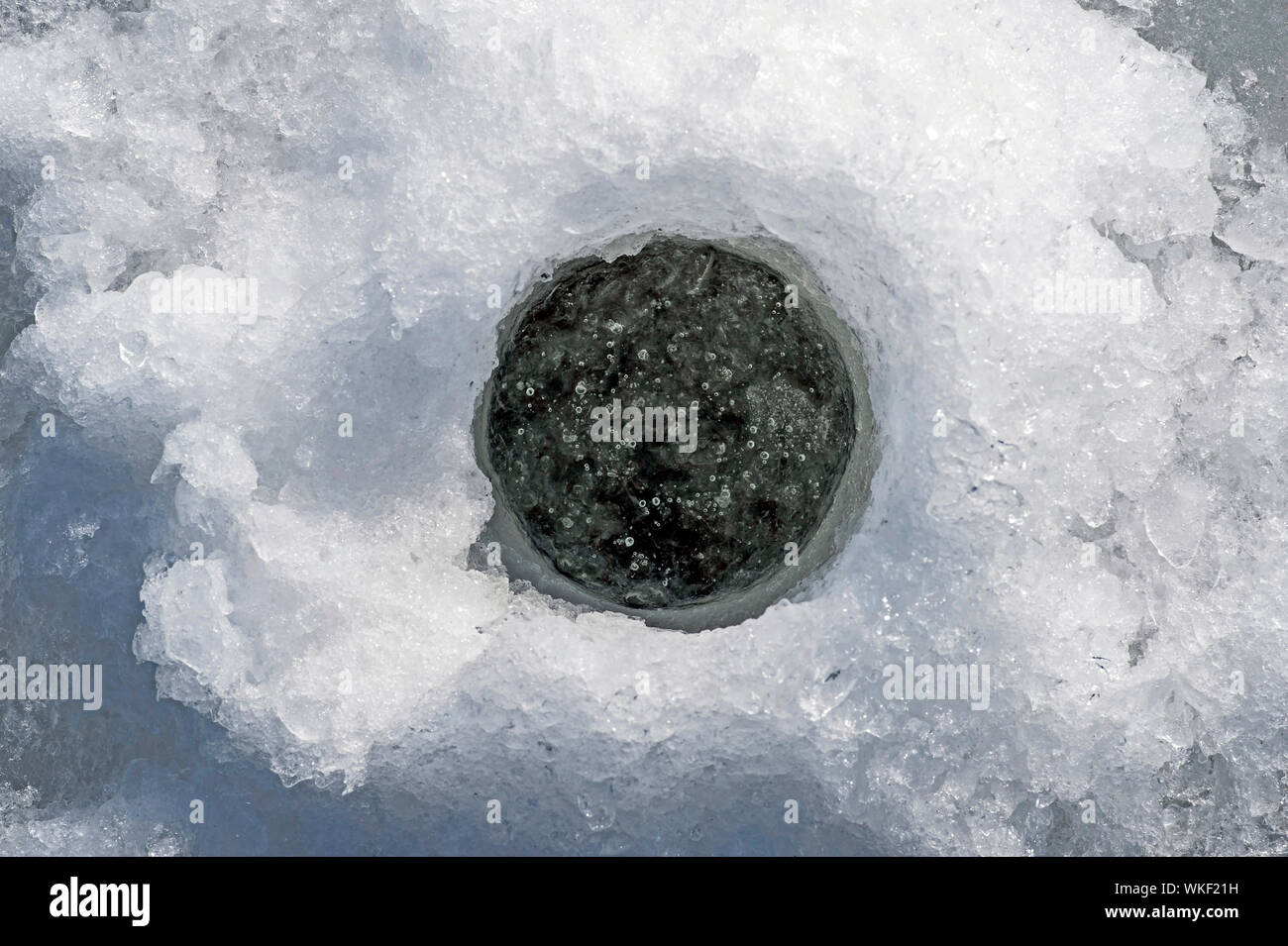 A frozen hole drilled in the ice by an ice drill. The view from the top ...