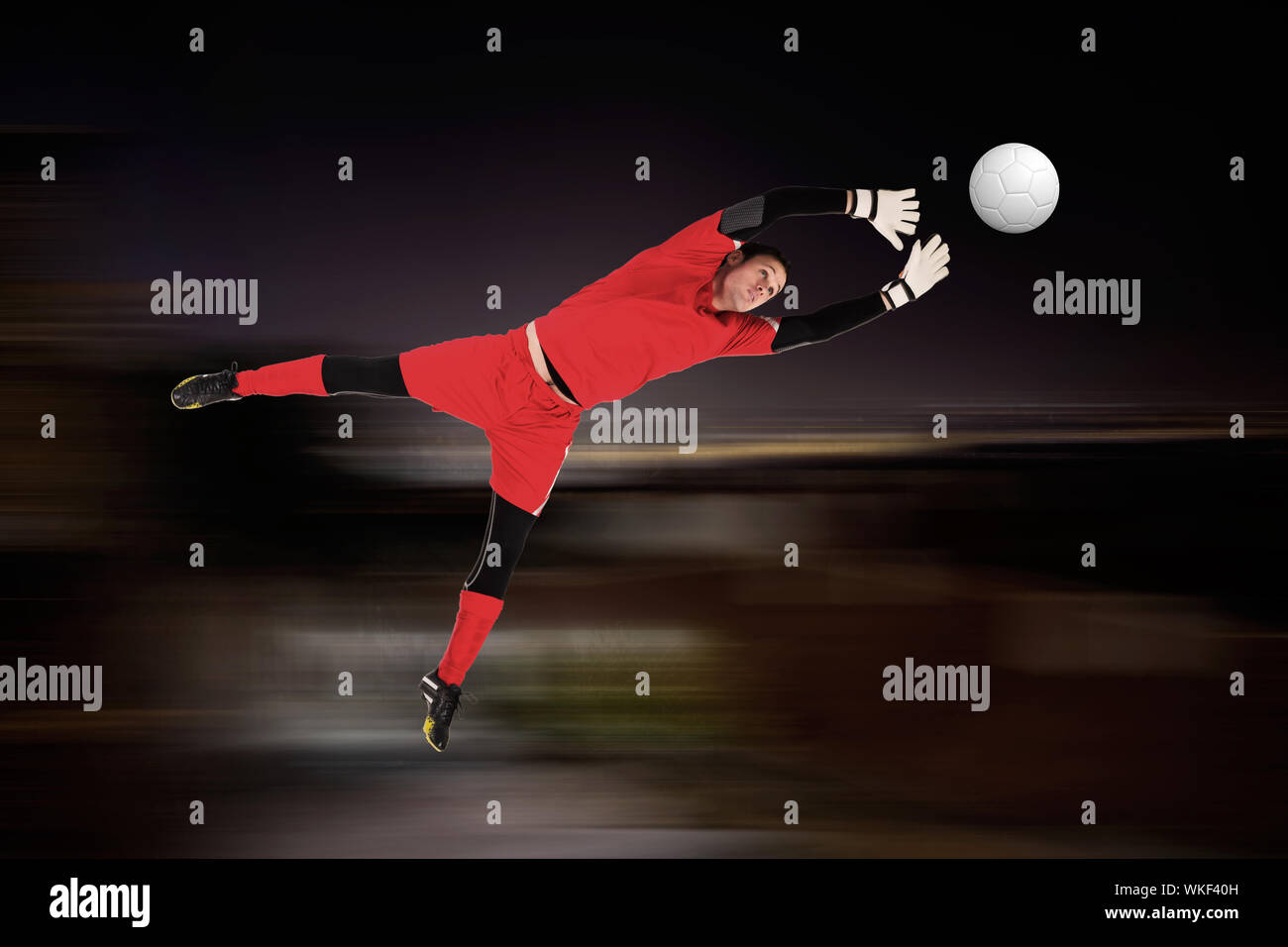 Fit goal keeper jumping up against blurry black background Stock Photo ...