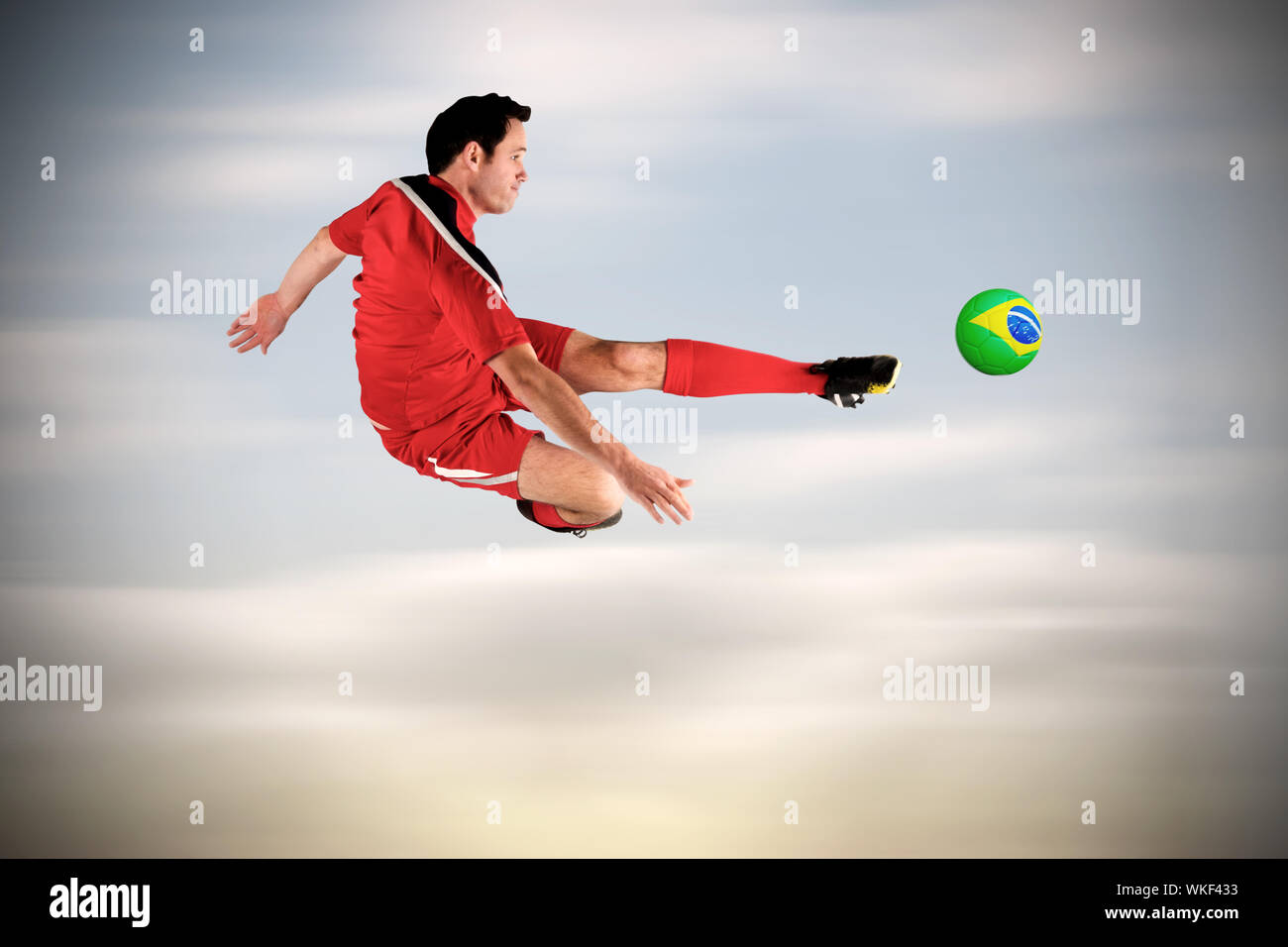 Football player in red kicking against beautiful blue sky with clouds ...