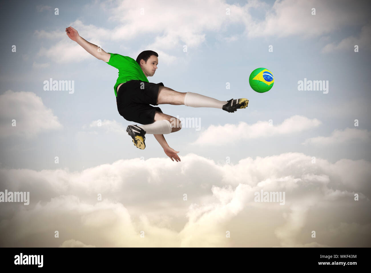 Football player in green kicking against beautiful blue sky with clouds ...