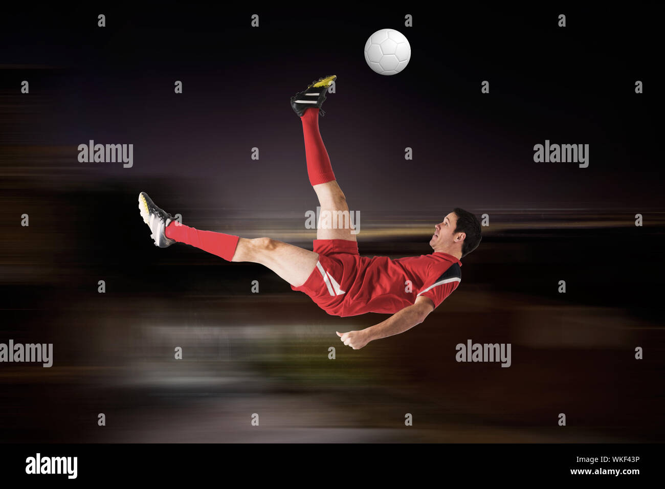 Football player in red kicking against black background Stock Photo - Alamy