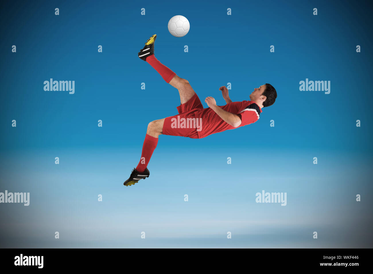 Football player in red kicking against blue background Stock Photo - Alamy
