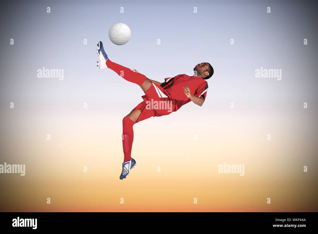 Football player in red kicking against beautiful orange and blue sky ...