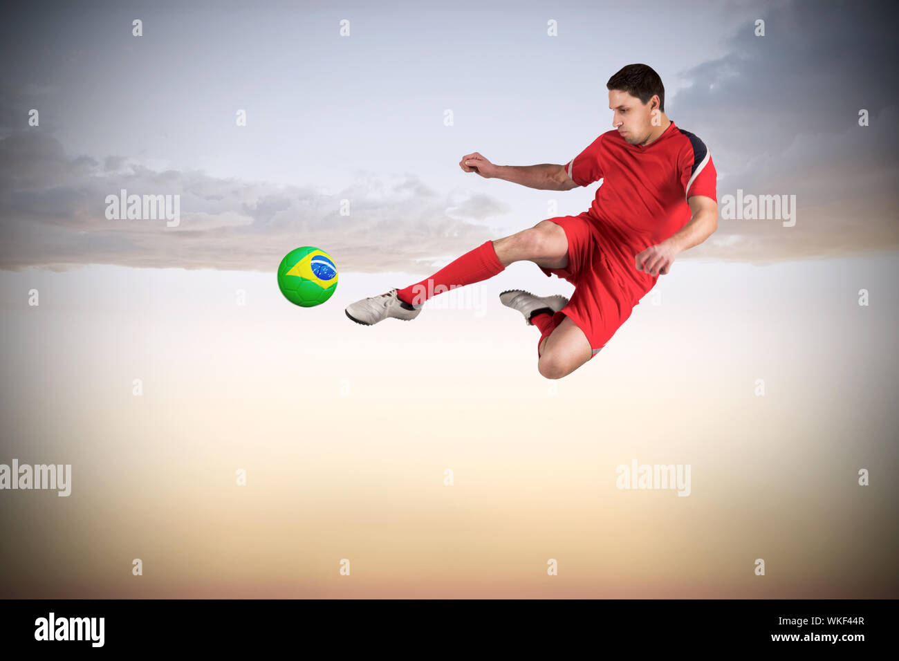 Fit football player jumping and kicking against beautiful orange and ...