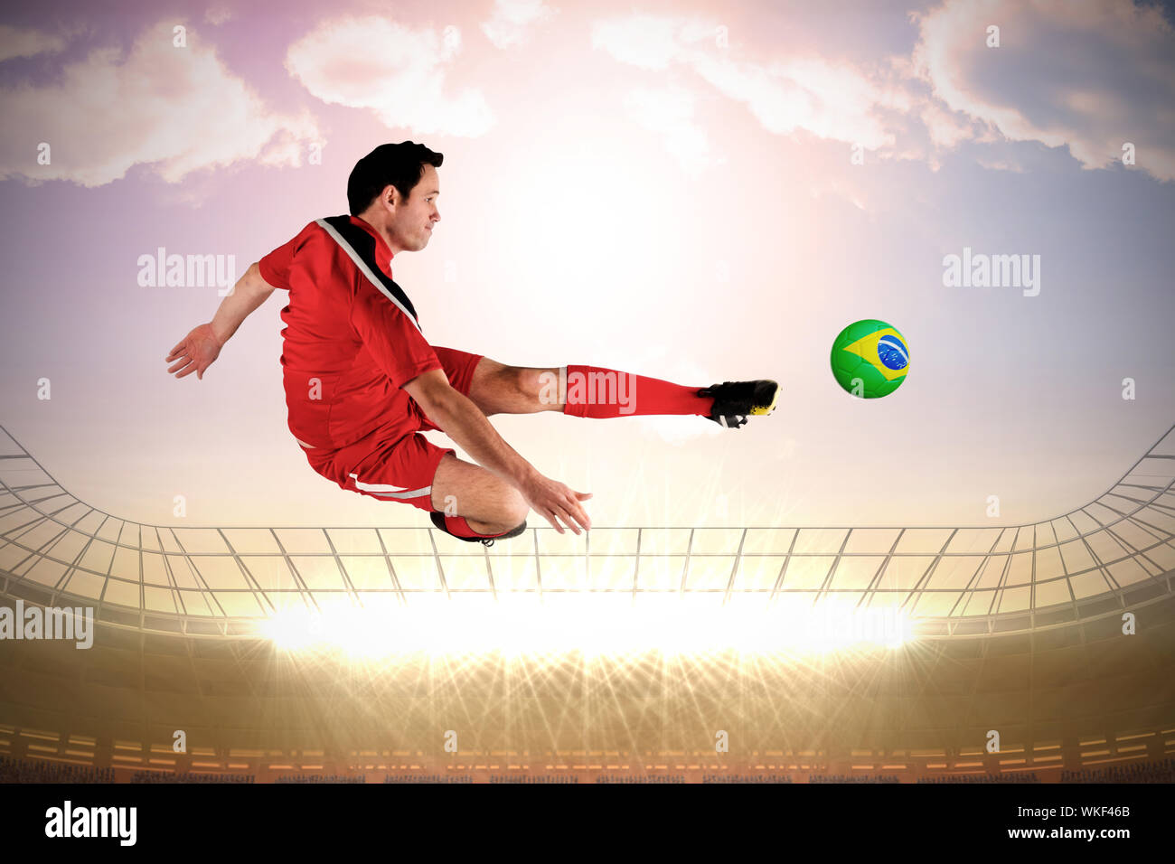 Football player in red kicking against large football stadium with ...