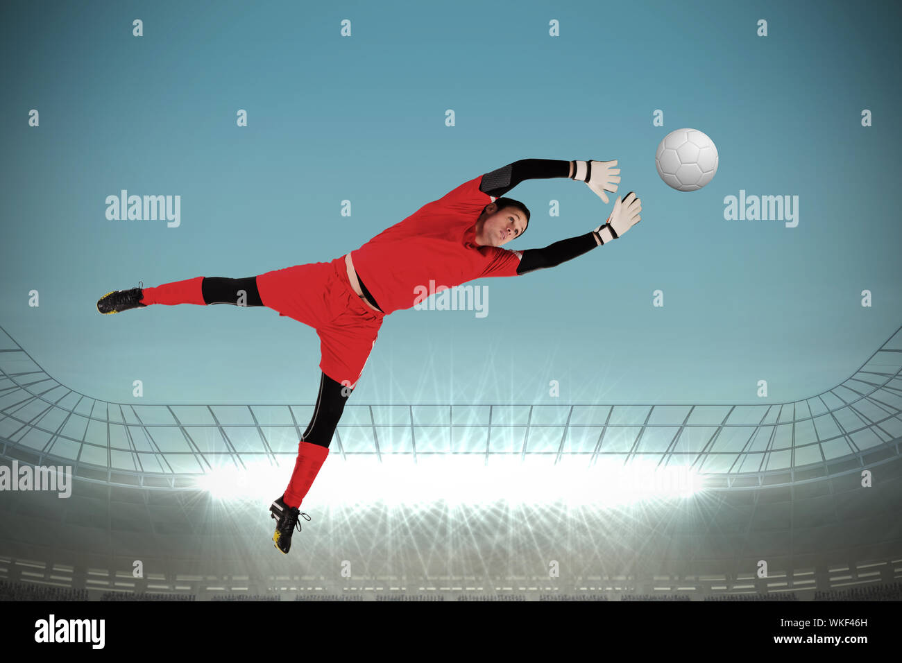 Fit goal keeper jumping up against large football stadium with ...