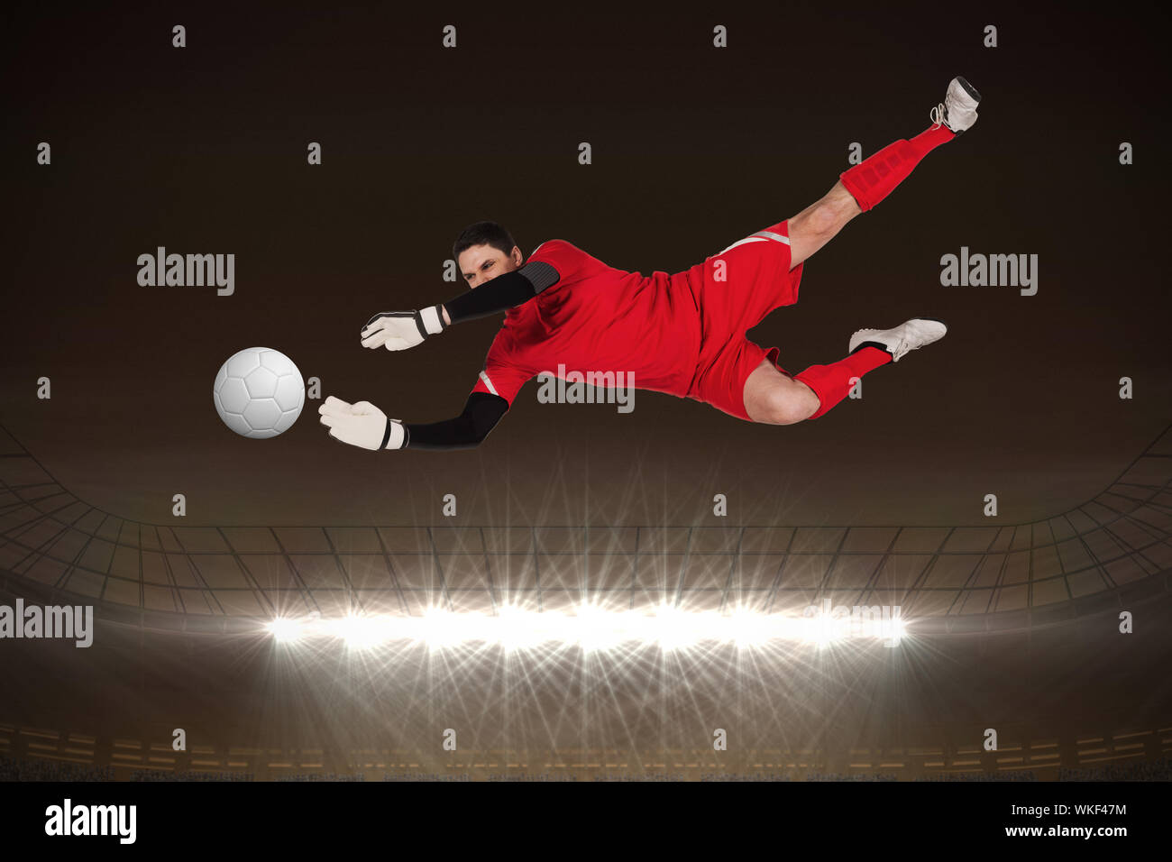 Fit goal keeper jumping up against large football stadium with ...