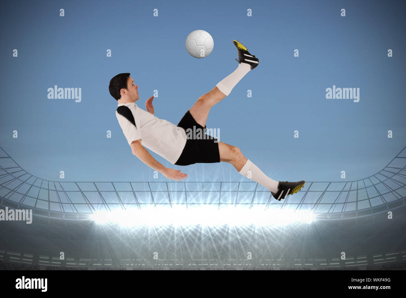 Football player in white kicking against large football stadium with ...