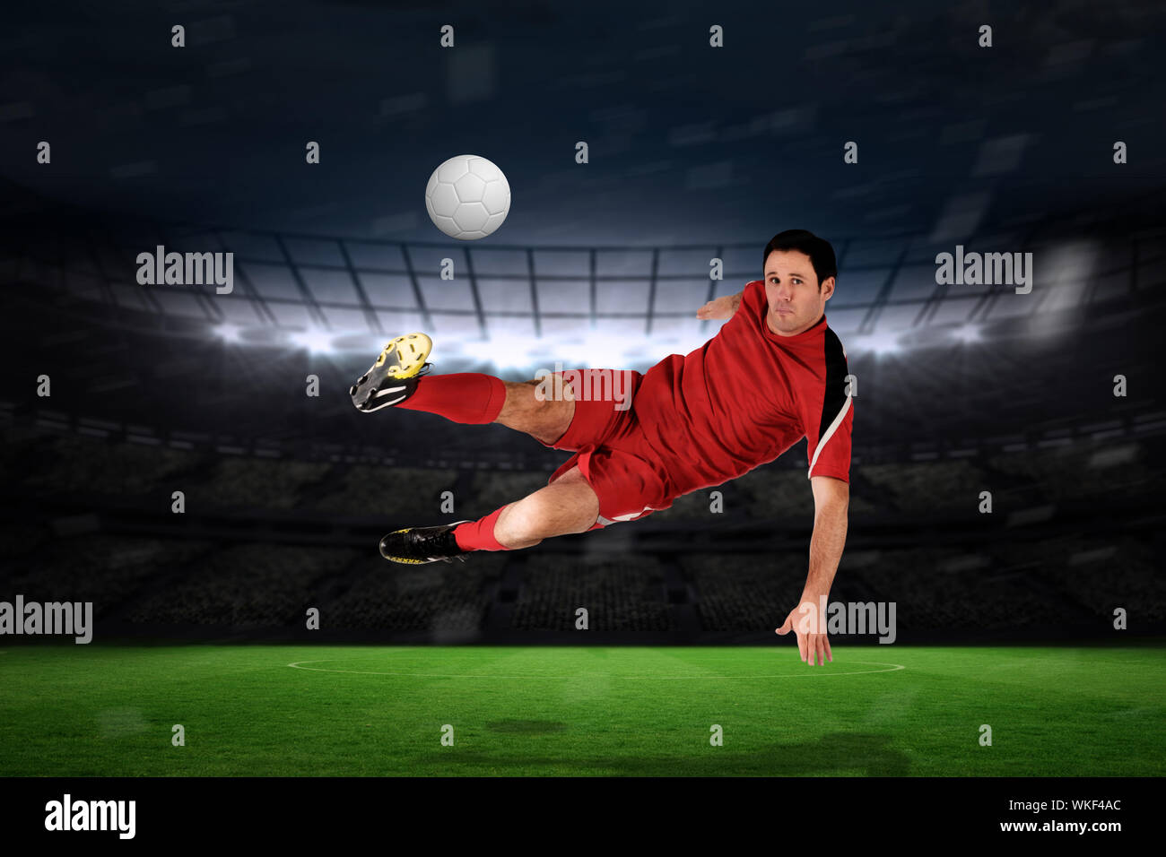Football player in red kicking against large football stadium with fans ...