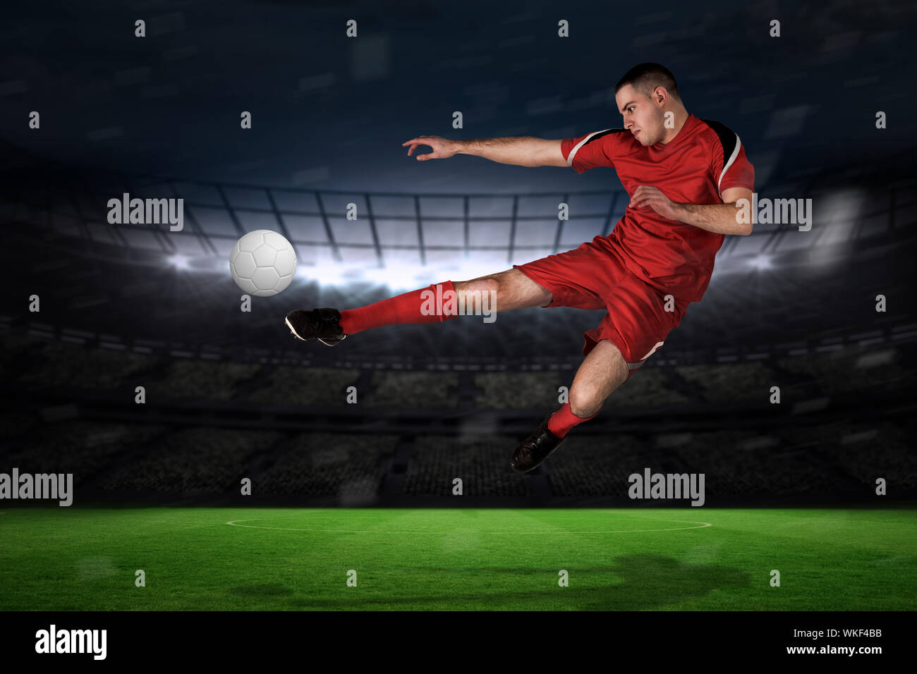 Fit football player playing and kicking against large football stadium ...