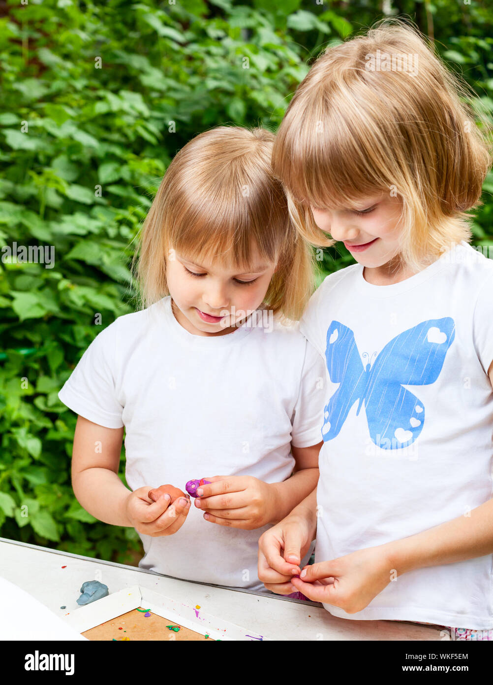Two little girls are playing with modelling clay outdoor Stock Photo ...