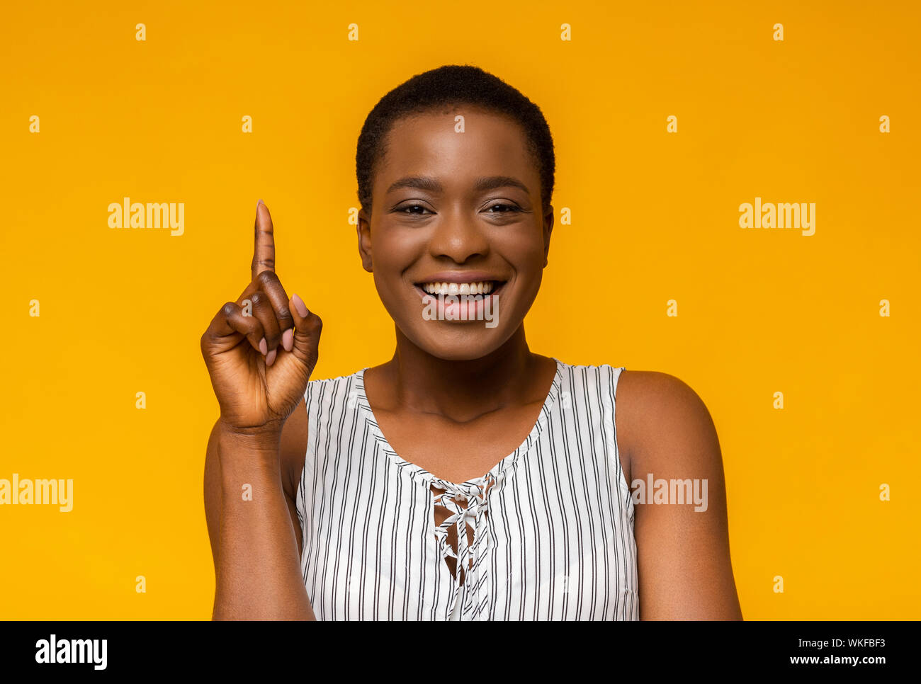 Playful young black woman pointing up on studio background Stock Photo ...