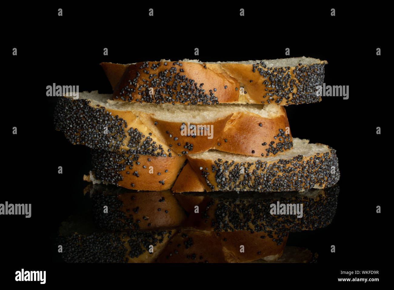 Group of three slices of twisted poppy seed bun isolated on black glass ...