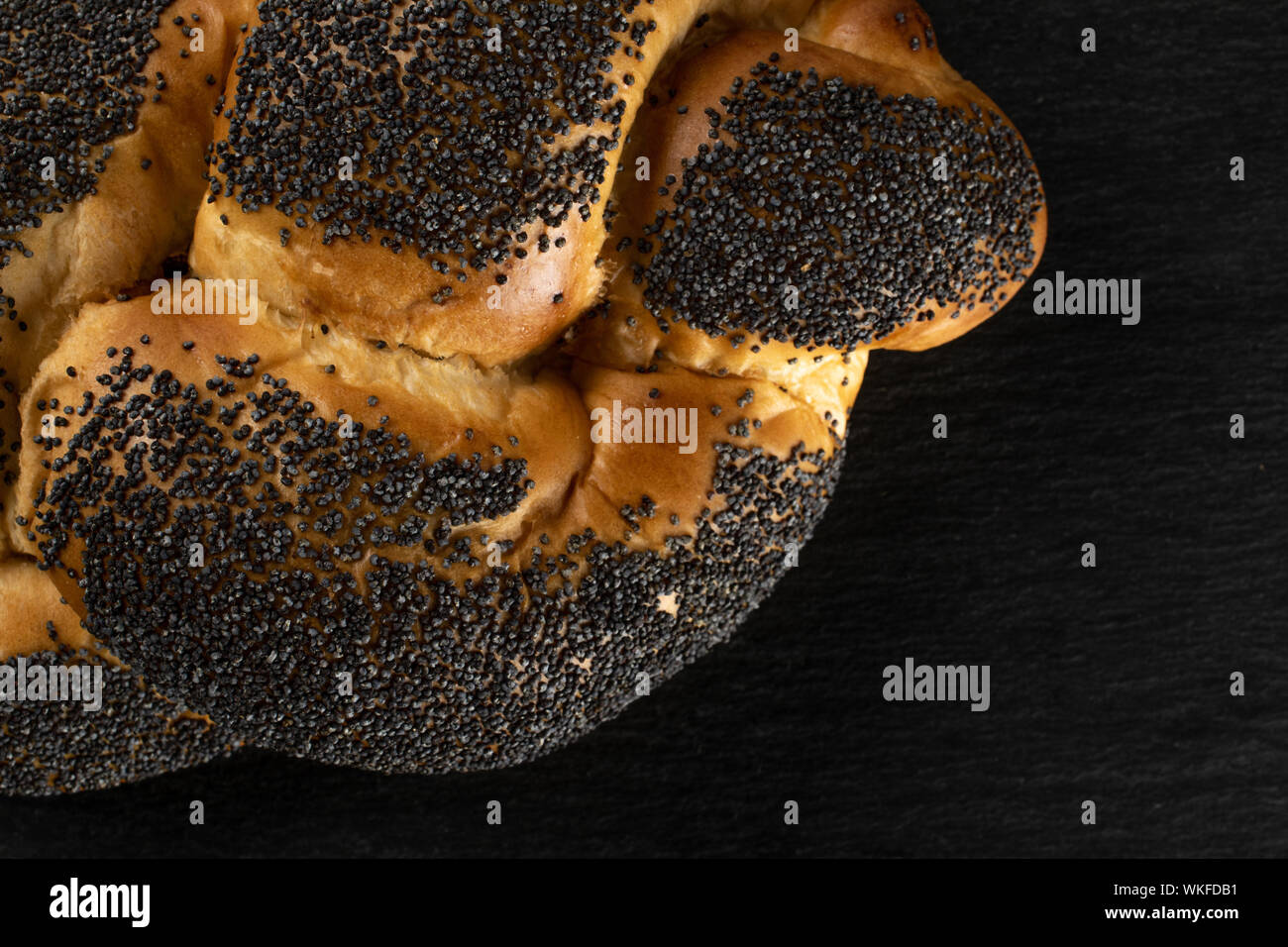 Closeup of one whole twisted poppy seed bun flatlay on grey stone Stock ...