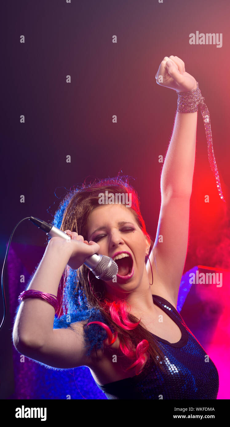 Young beautiful pop star with hand raised on stage Stock Photo - Alamy