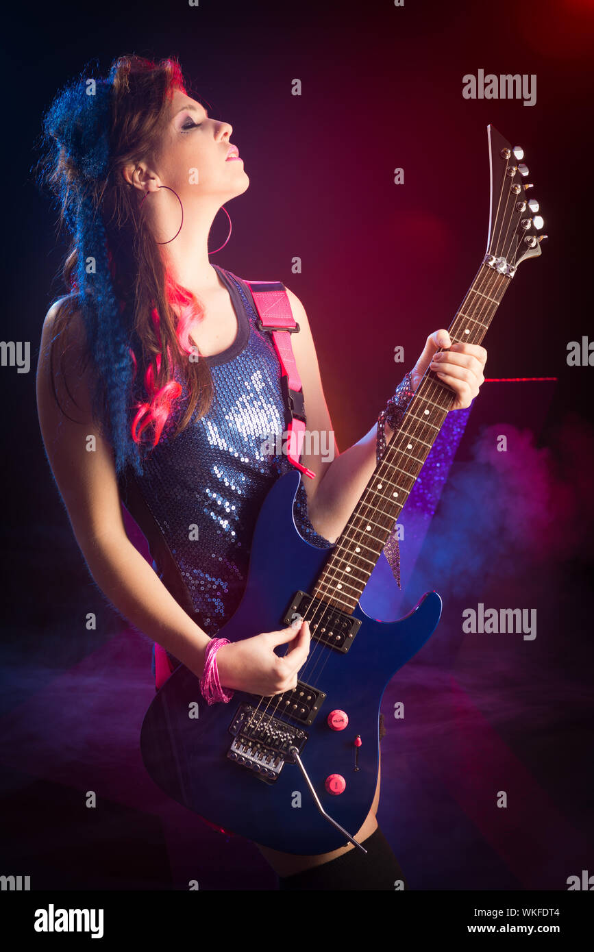 Young teenager rock star singing and playing electric guitar on stage ...