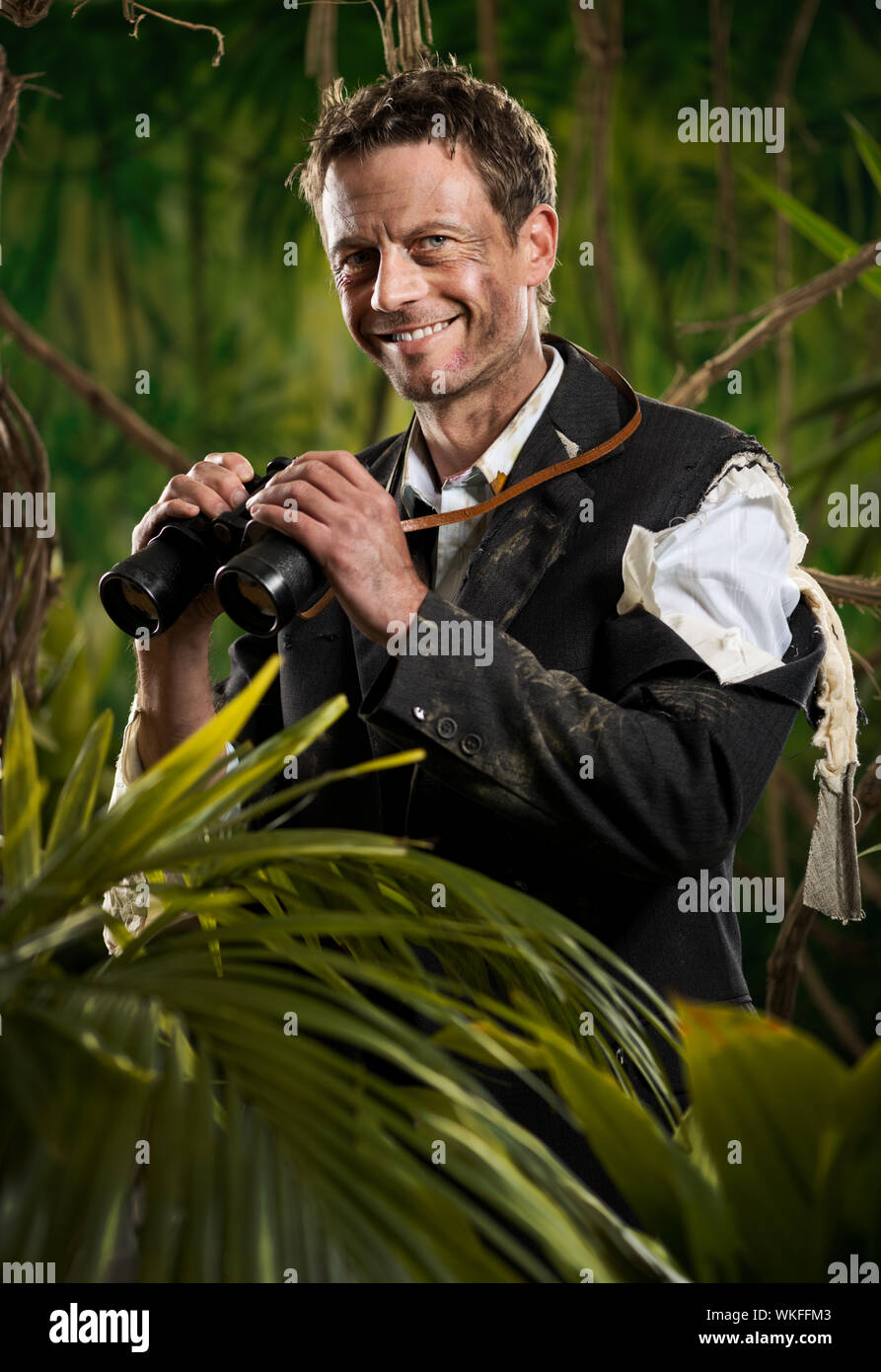 Confident businessman holding binoculars and exploring jungle Stock ...