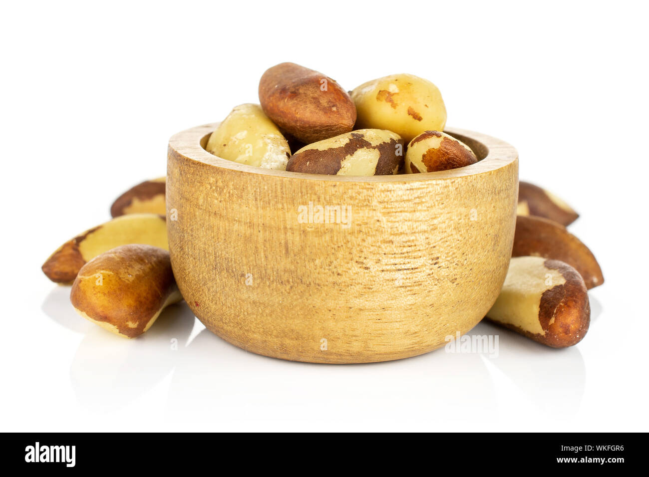 Lot of whole raw brown brazil nut in tiny wooden bowl isolated on white ...