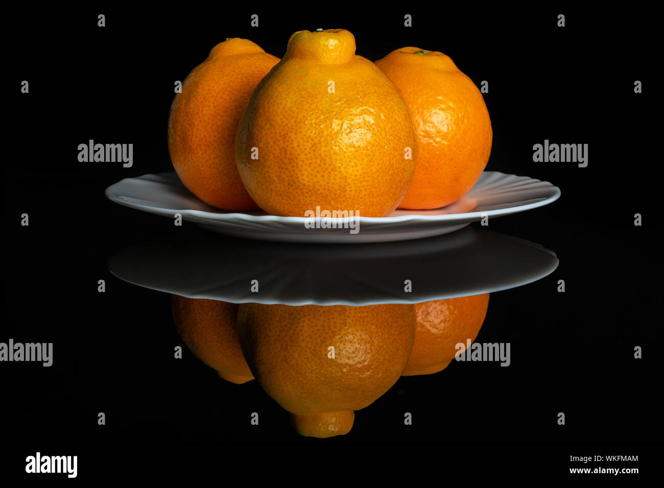 Group of three whole fresh orange tangelo minneola on white ceramic ...