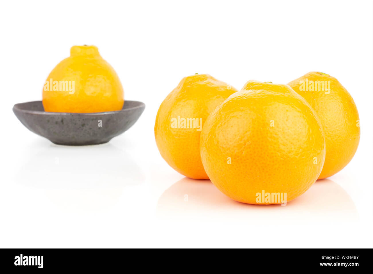 Group of four whole fresh orange tangelo minneola in dark ceramic bowl ...
