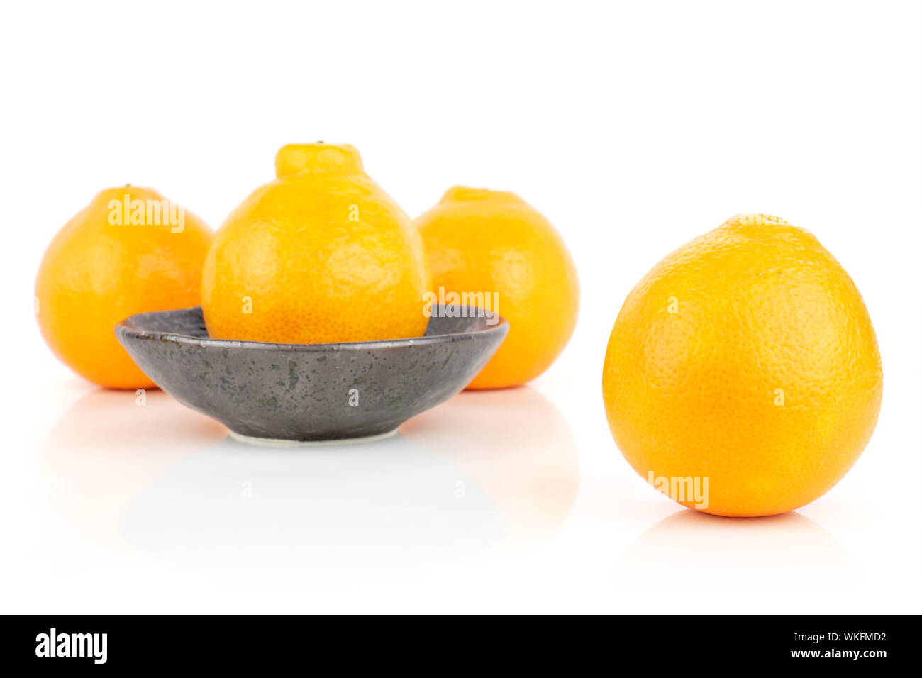 Group of four whole fresh orange tangelo minneola in dark ceramic bowl ...