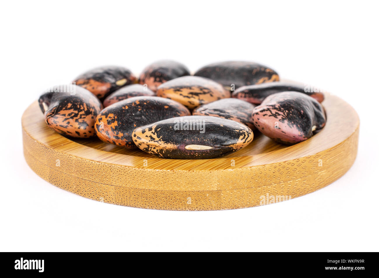 Lot of whole stained purple bean on round bamboo coaster isolated on ...