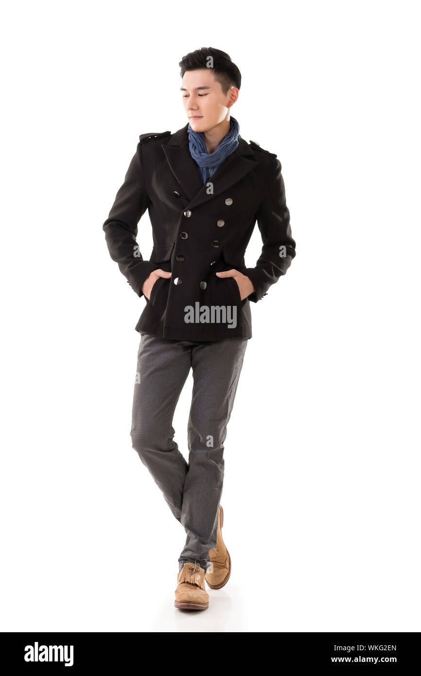 Attractive young Asian man in winter coat, full length portrait ...