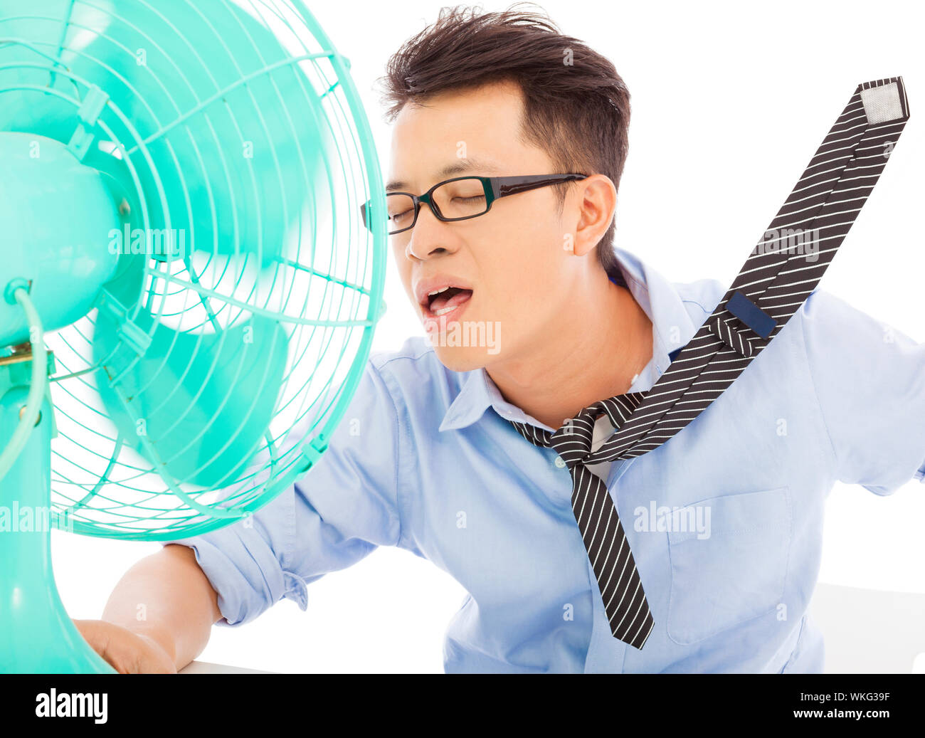 Young man cooling face under wind of fan Stock Photo - Alamy