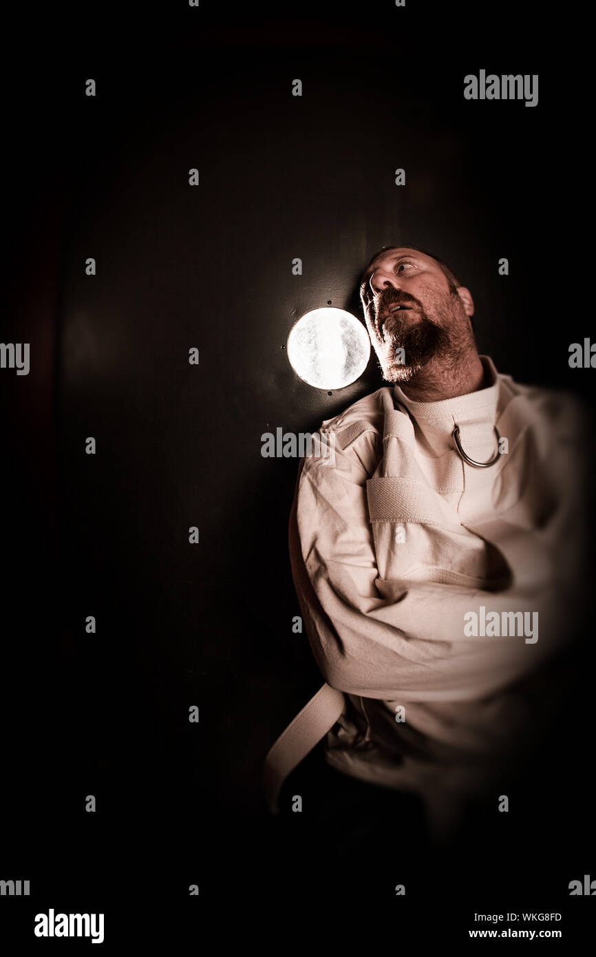 Photo of an insane man in his forties wearing a straitjacket standing ...