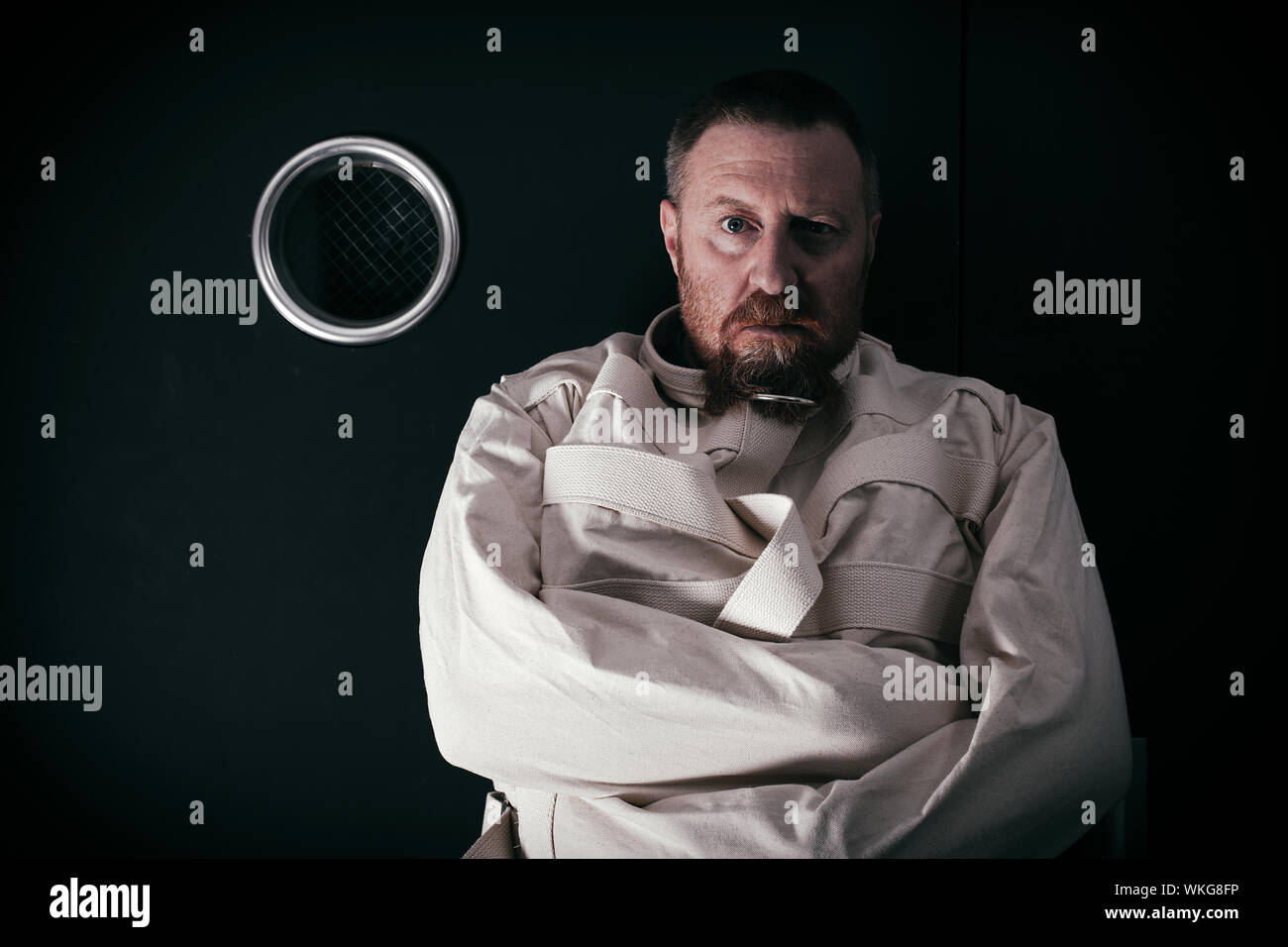 Photo of an insane man in his forties wearing a straitjacket standing ...