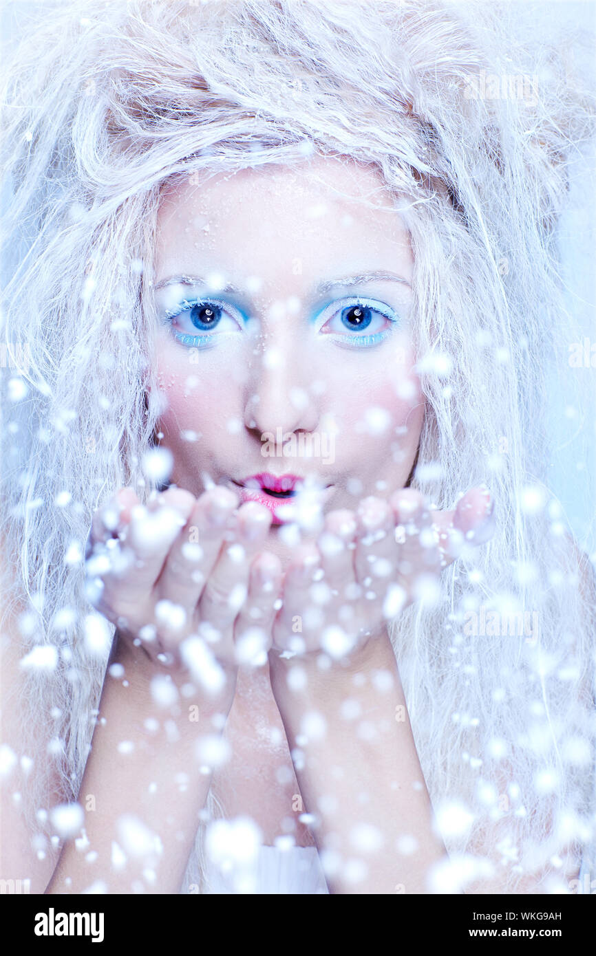 portrait of beautiful blonde frozen fairy girl blowing snow flakes from ...